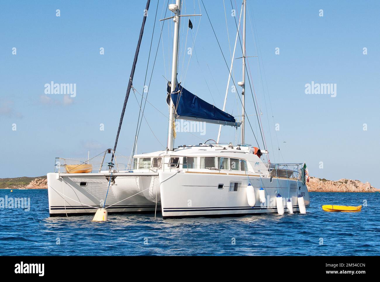 Catamaran with small dinghy moored to mooring buoy, Sardinia, Italy ...