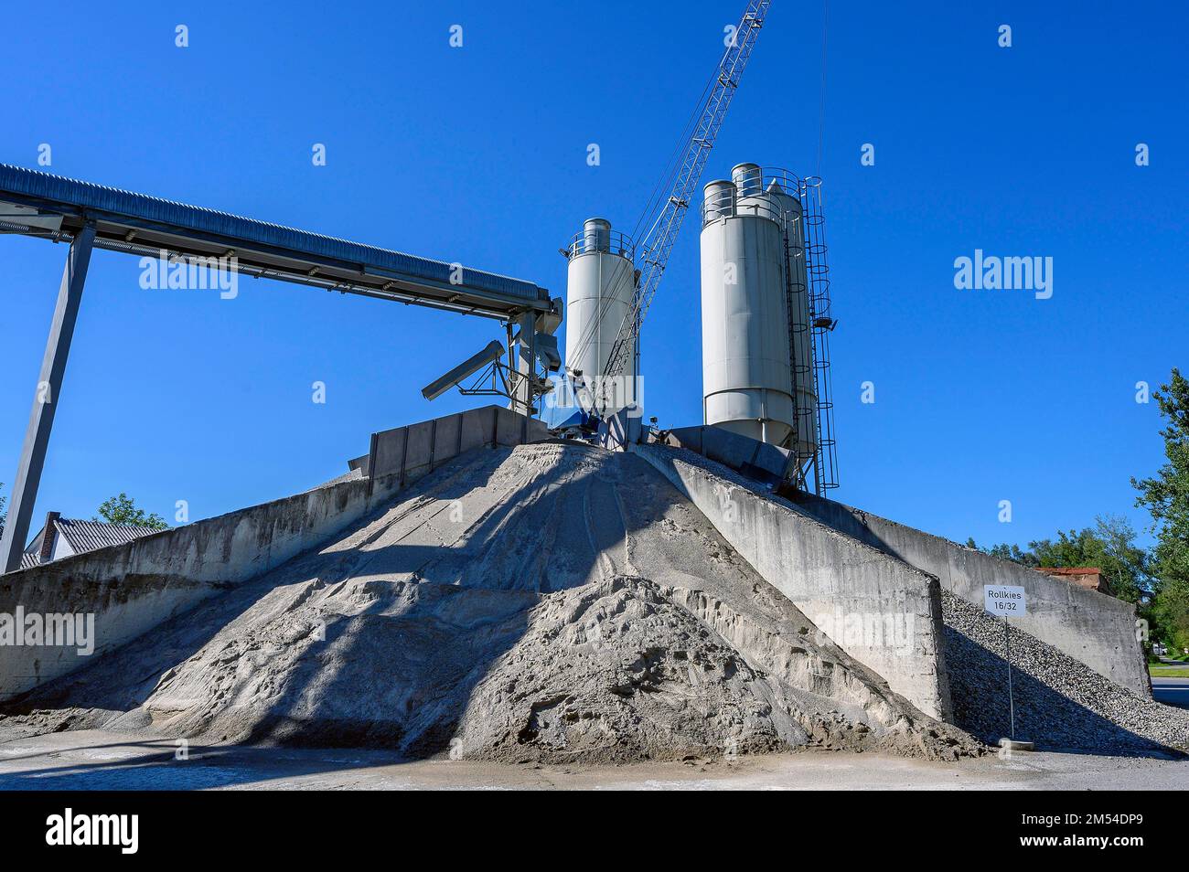 Steel silos and shovel crane with gravel piles and conveyor belt ...