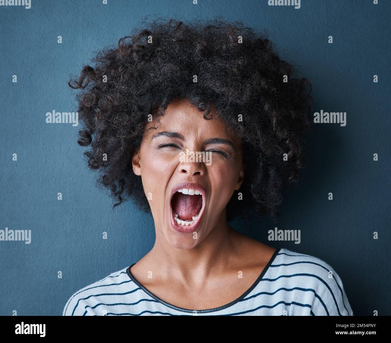 Nooooo. Studio portrait of an attractive young woman screaming against a blue background Stock ...