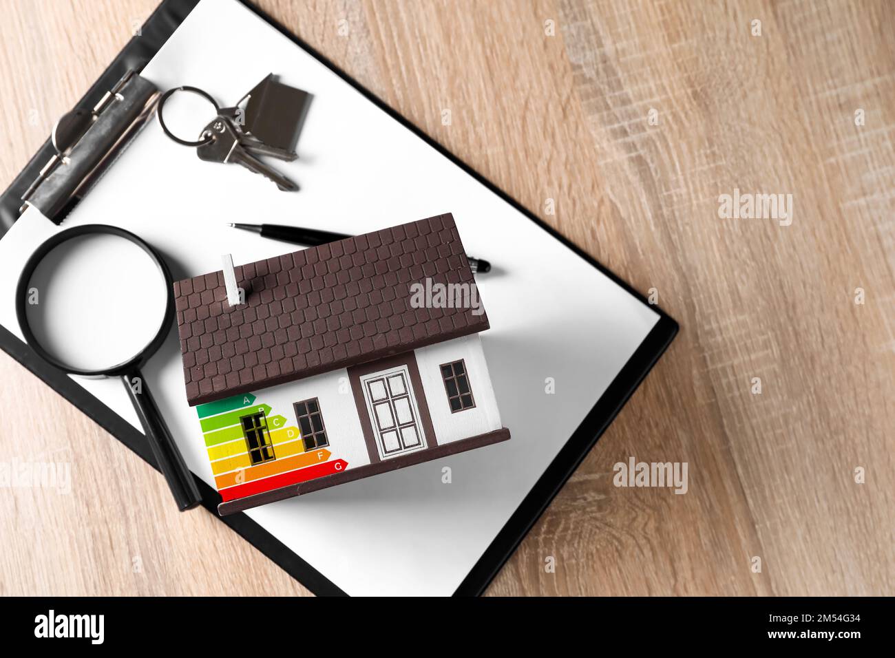 Model of house with key, magnifier and clipboard on wooden background ...