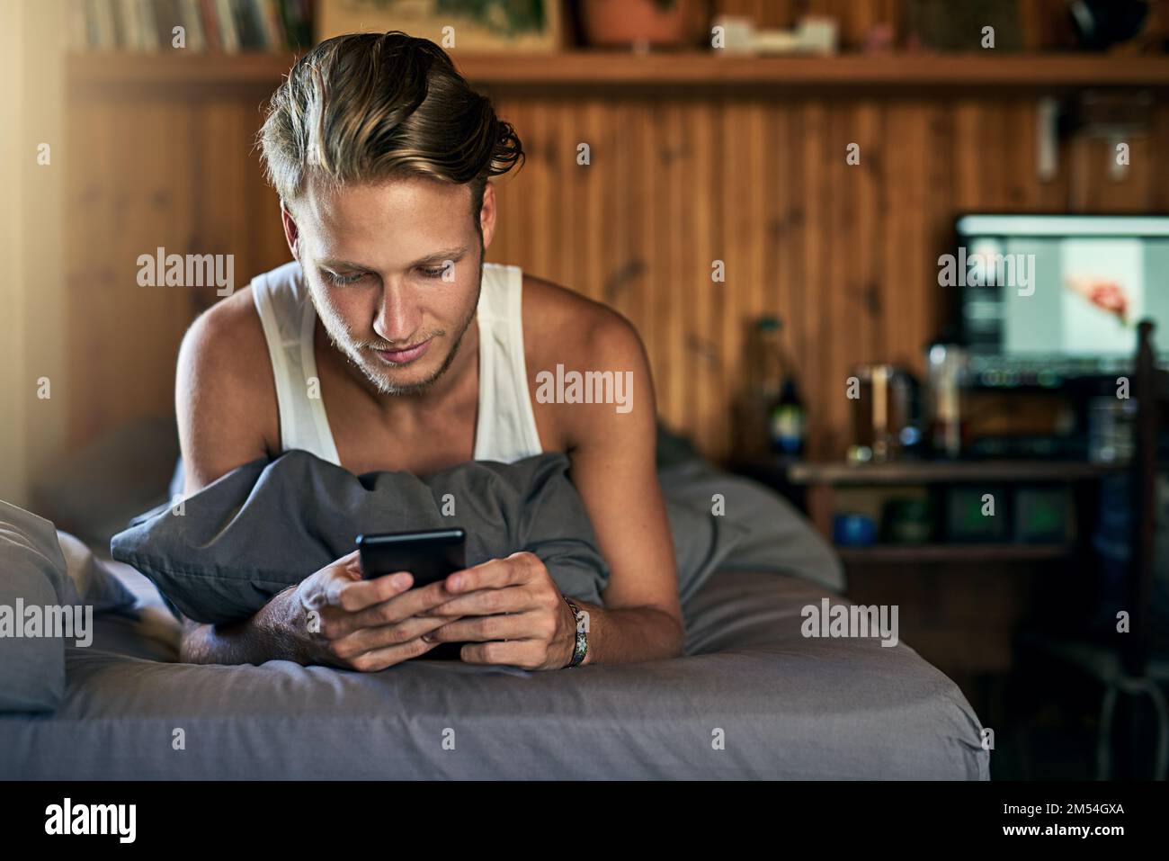Texting is a part of his morning routine. a young man texting on his ...