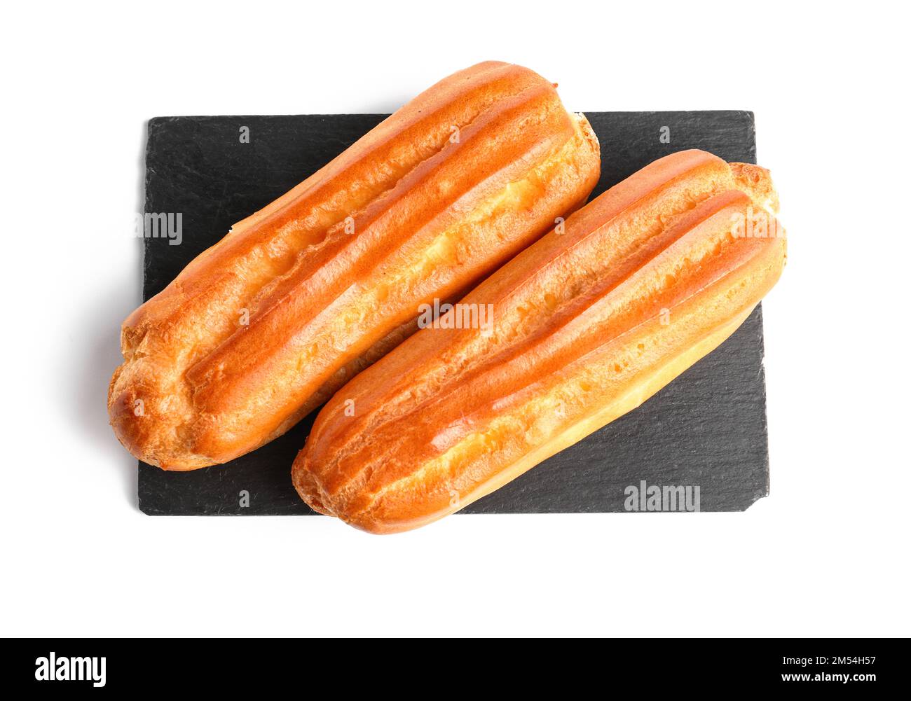 Slate board with tasty eclairs on white background Stock Photo - Alamy
