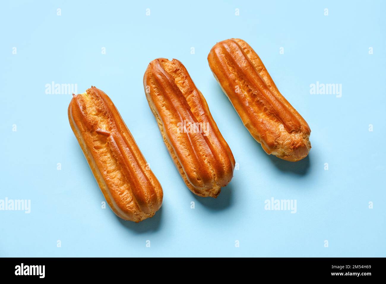 Sweet eclairs on blue background Stock Photo - Alamy