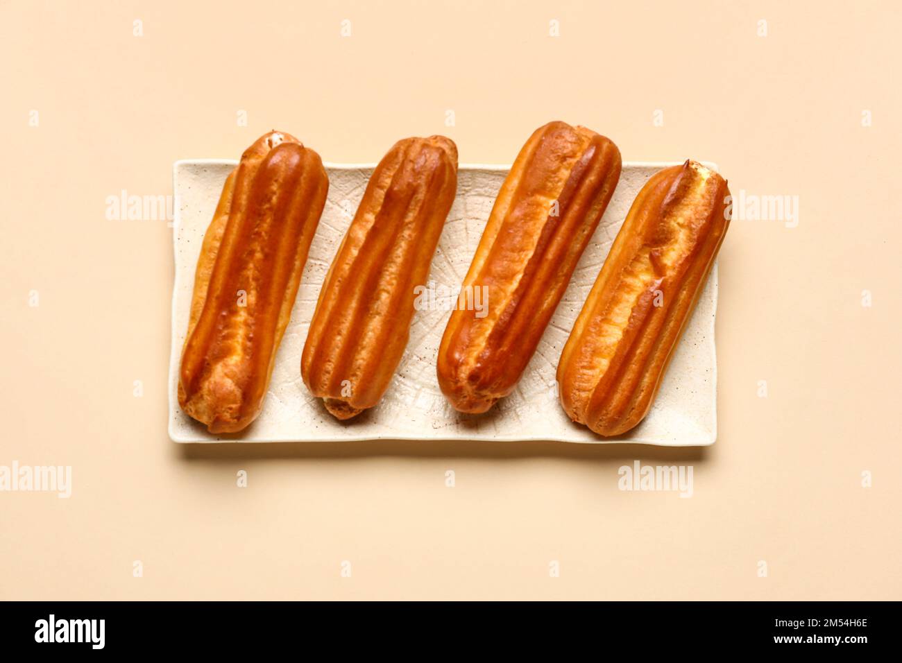 Plate with sweet eclairs on color background Stock Photo - Alamy