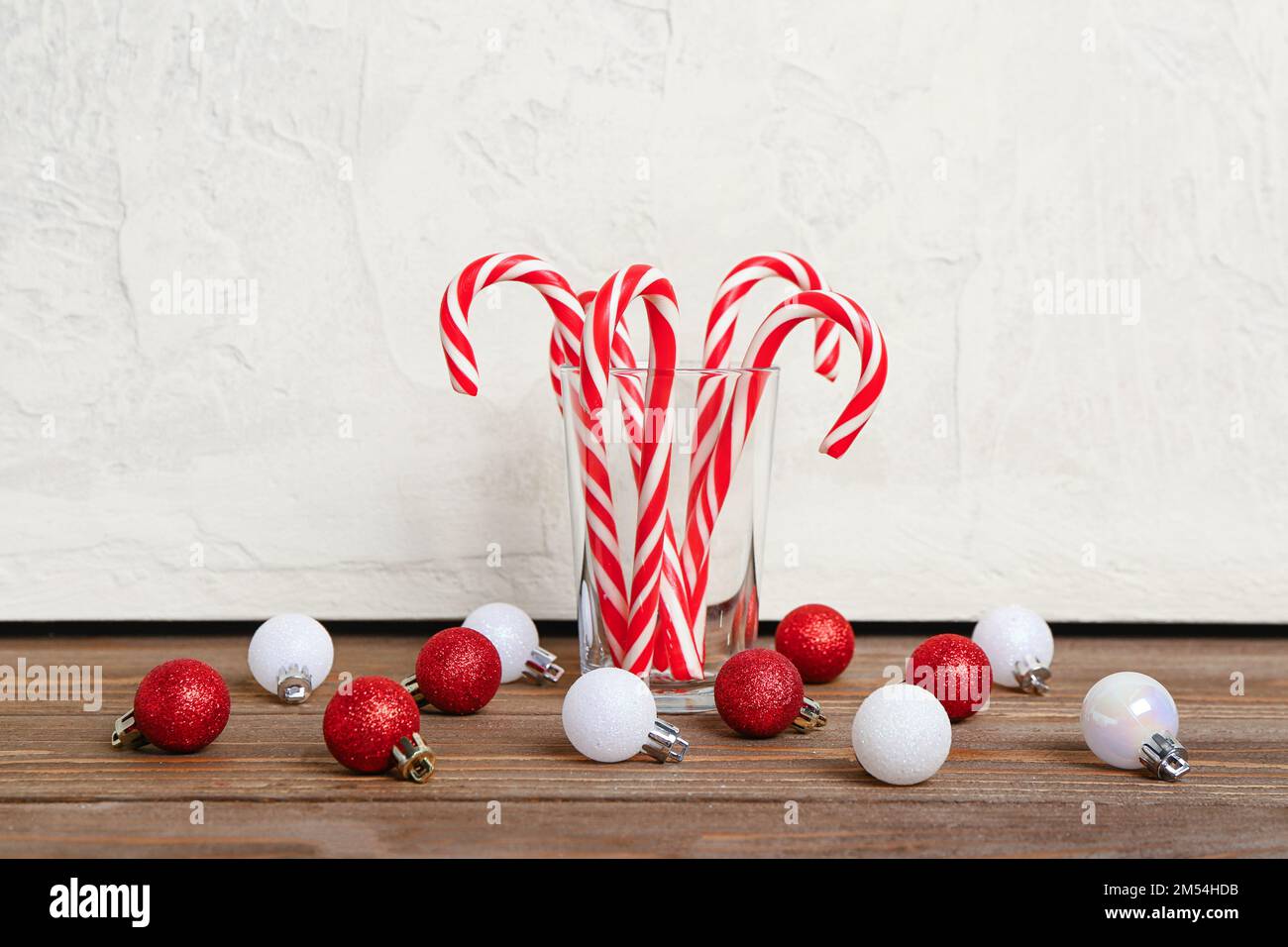 Glass with tasty candy canes and Christmas balls on wooden table Stock ...