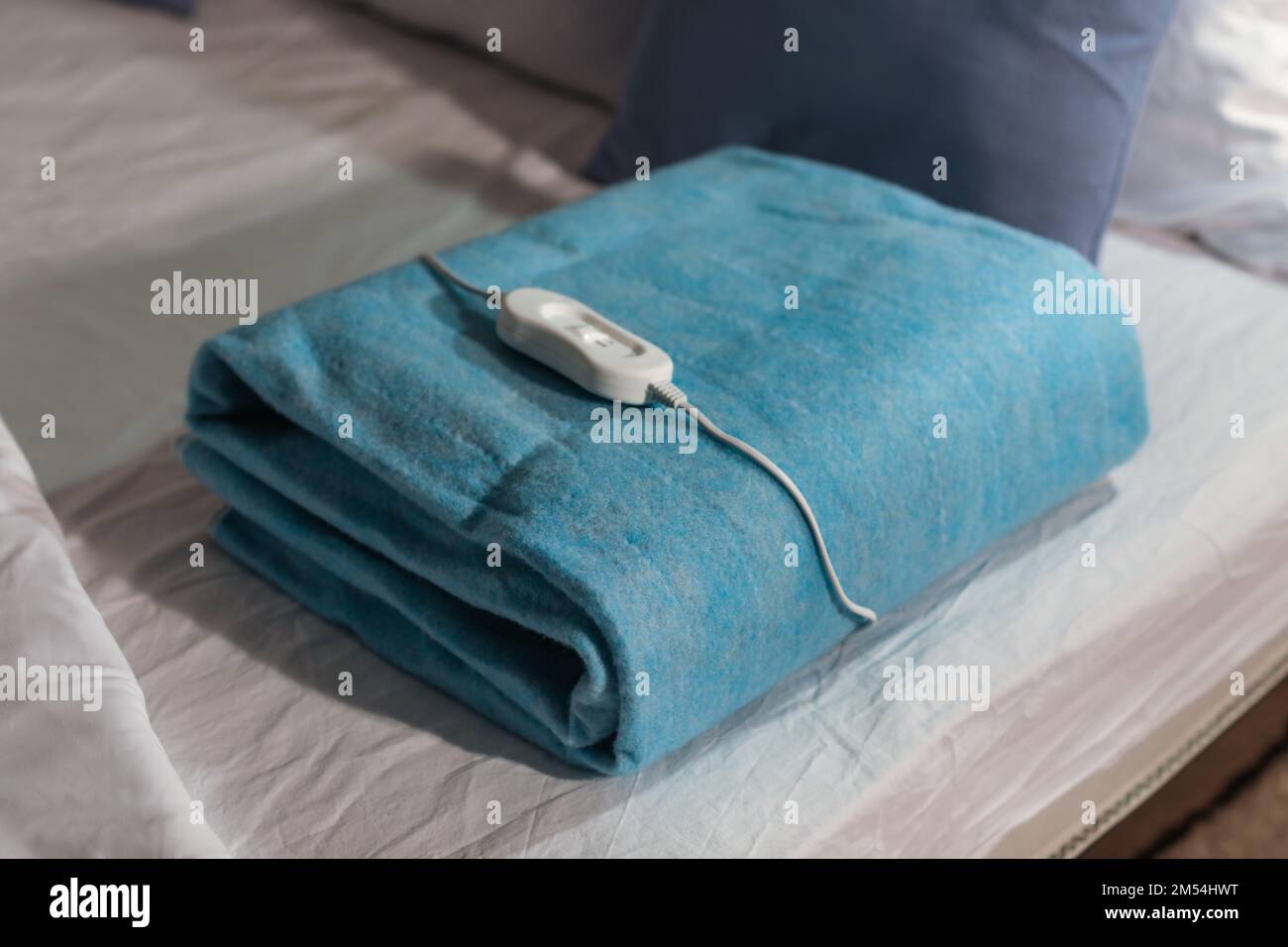 Folded electric heating pad with controller on bed at night, closeup ...