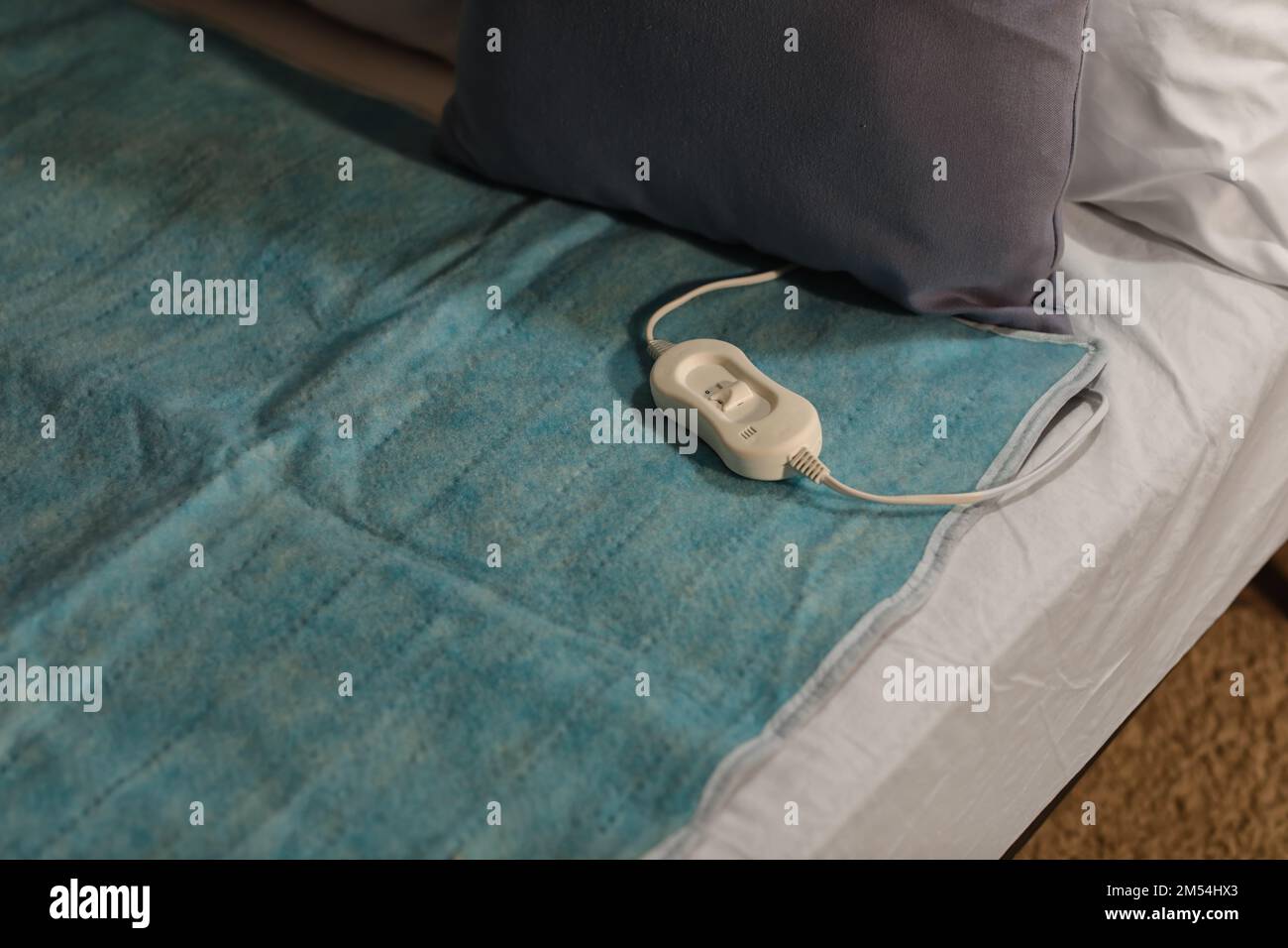 Electric heating pad with controller on bed at night, closeup Stock ...