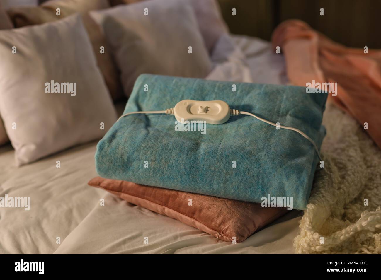 Electric heating pad with pillow on bed at night, closeup Stock Photo ...