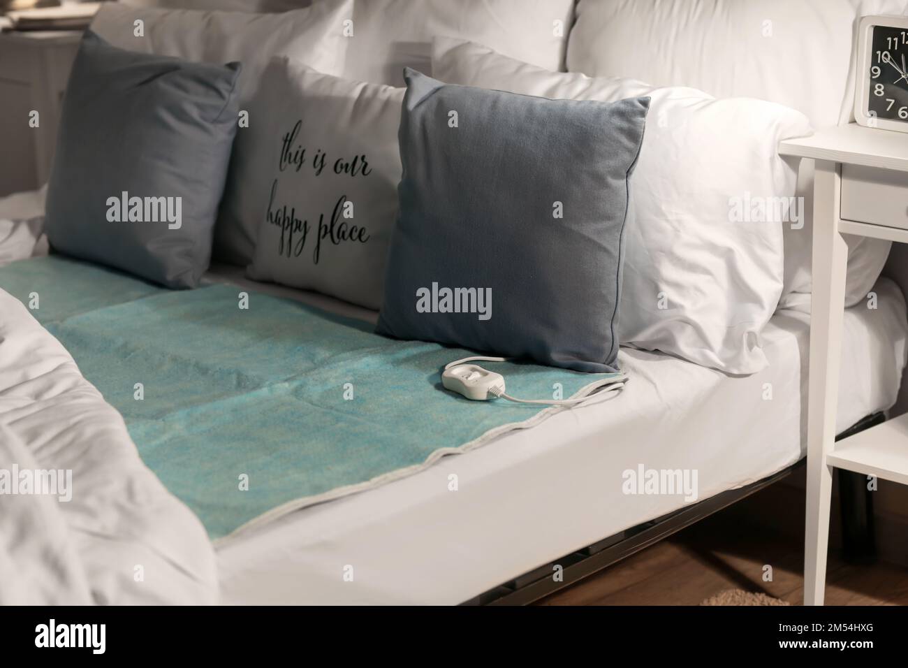 Bed with electric heating pad in bedroom at night Stock Photo - Alamy