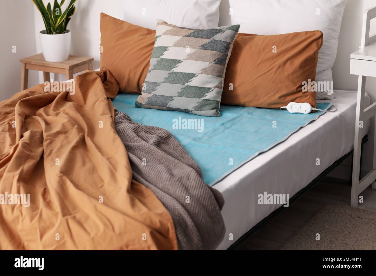 Bed with pillows and electric heating pad in bedroom Stock Photo - Alamy