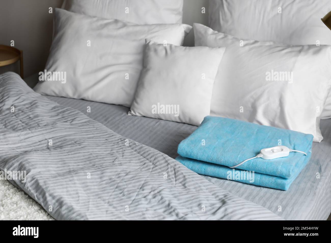 Folded electric heating pad with controller on bed in bedroom Stock ...