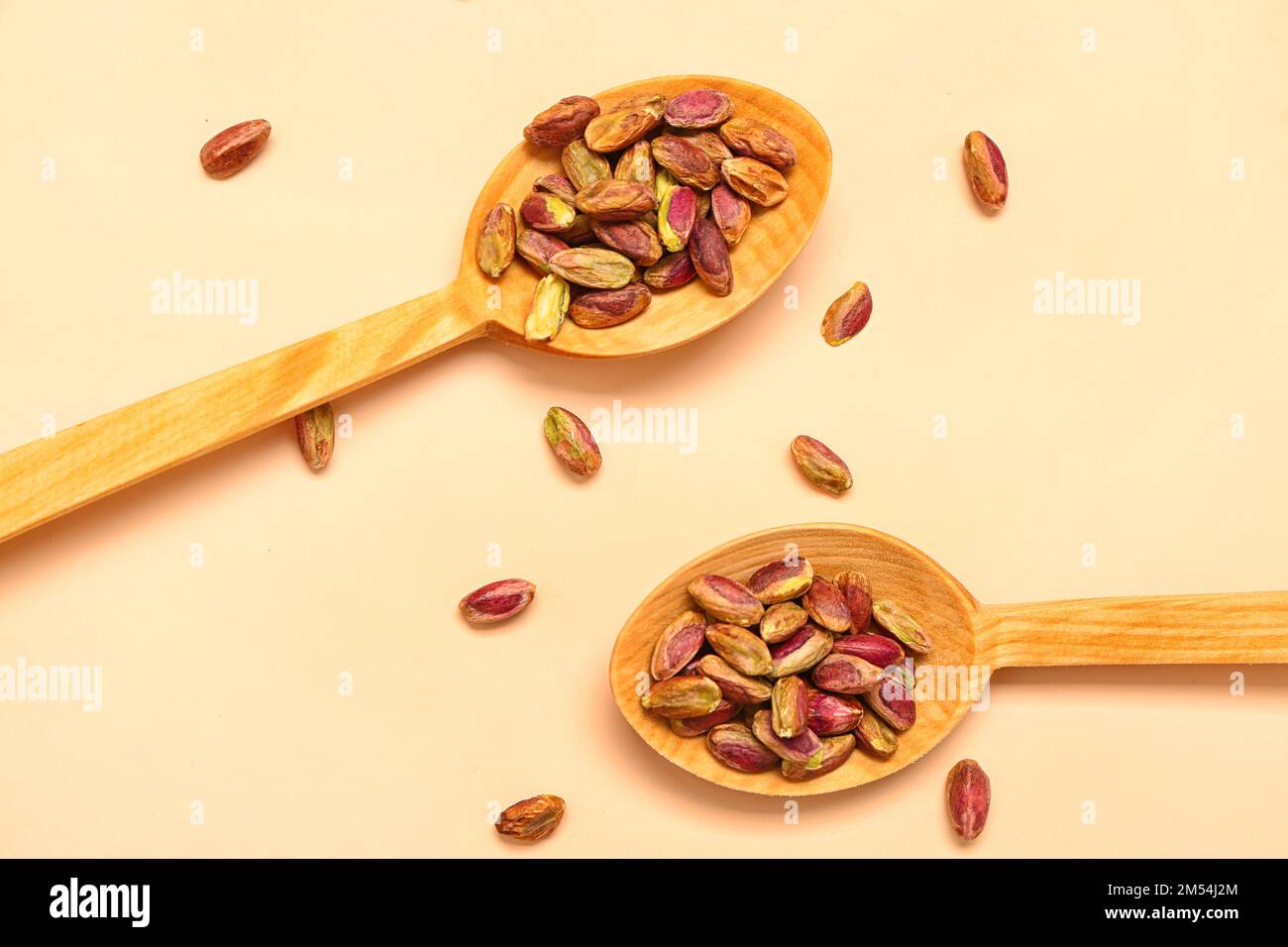 Spoons with tasty pistachio nuts on beige background Stock Photo - Alamy