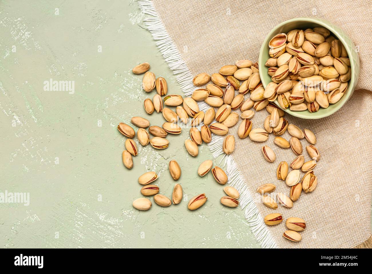 Napkin with overturned bowl of tasty pistachios and scattered nuts on ...