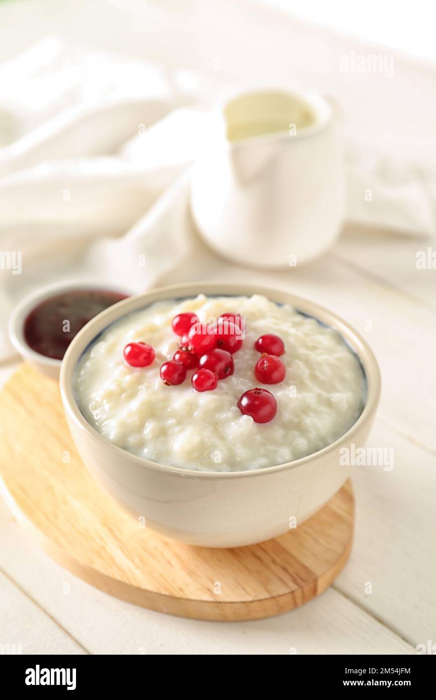 Bowl with delicious rice pudding, cranberry and jam on white wooden ...