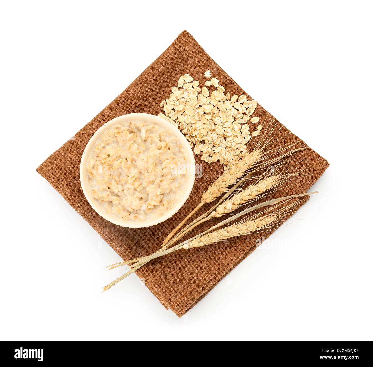 Bowl with tasty oatmeal, wheat ears and heap of flakes isolated on ...