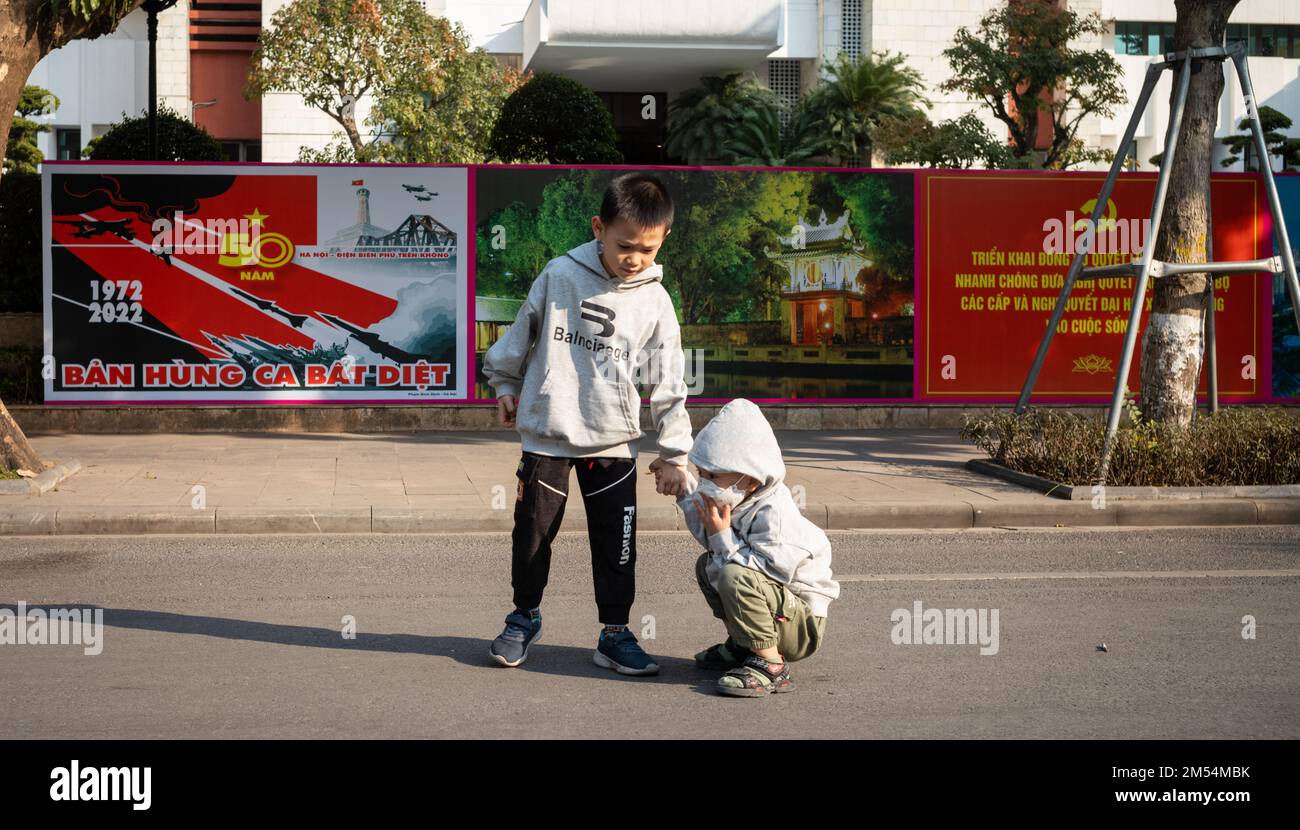 A young boy helps his baby brother near Communist party propaganda ...