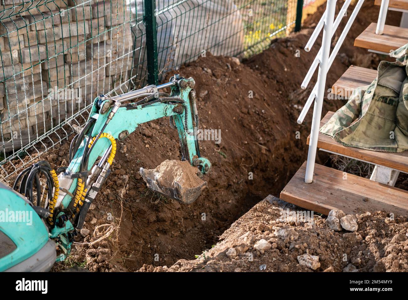 Mini excavator digs a trench to lay pipes. Close up of an excavator ...