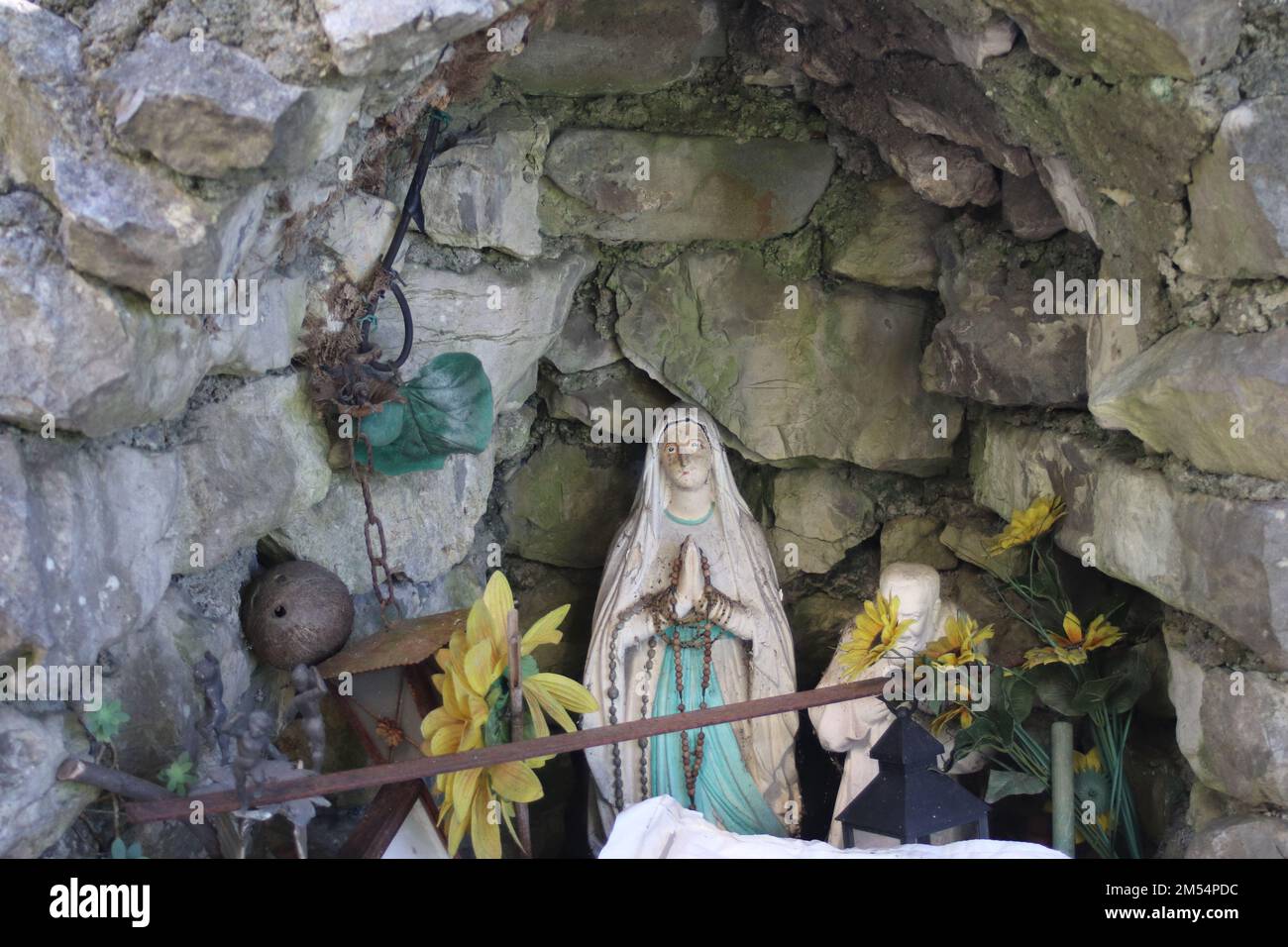 A closeup of people's home grotto with flowers in the corner of a cave ...