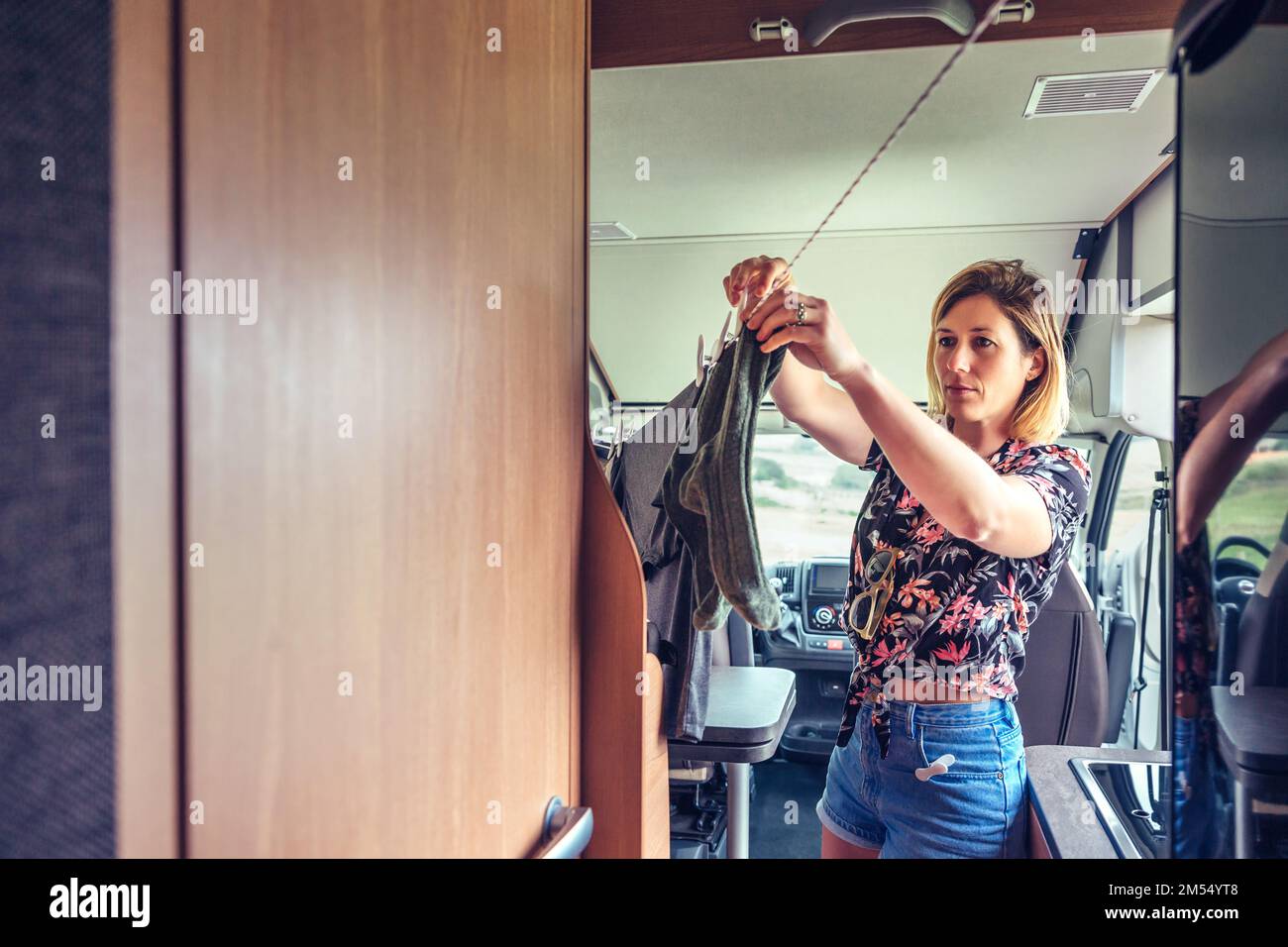 Woman hanging clothes on a rope inside her camper van Stock Photo - Alamy