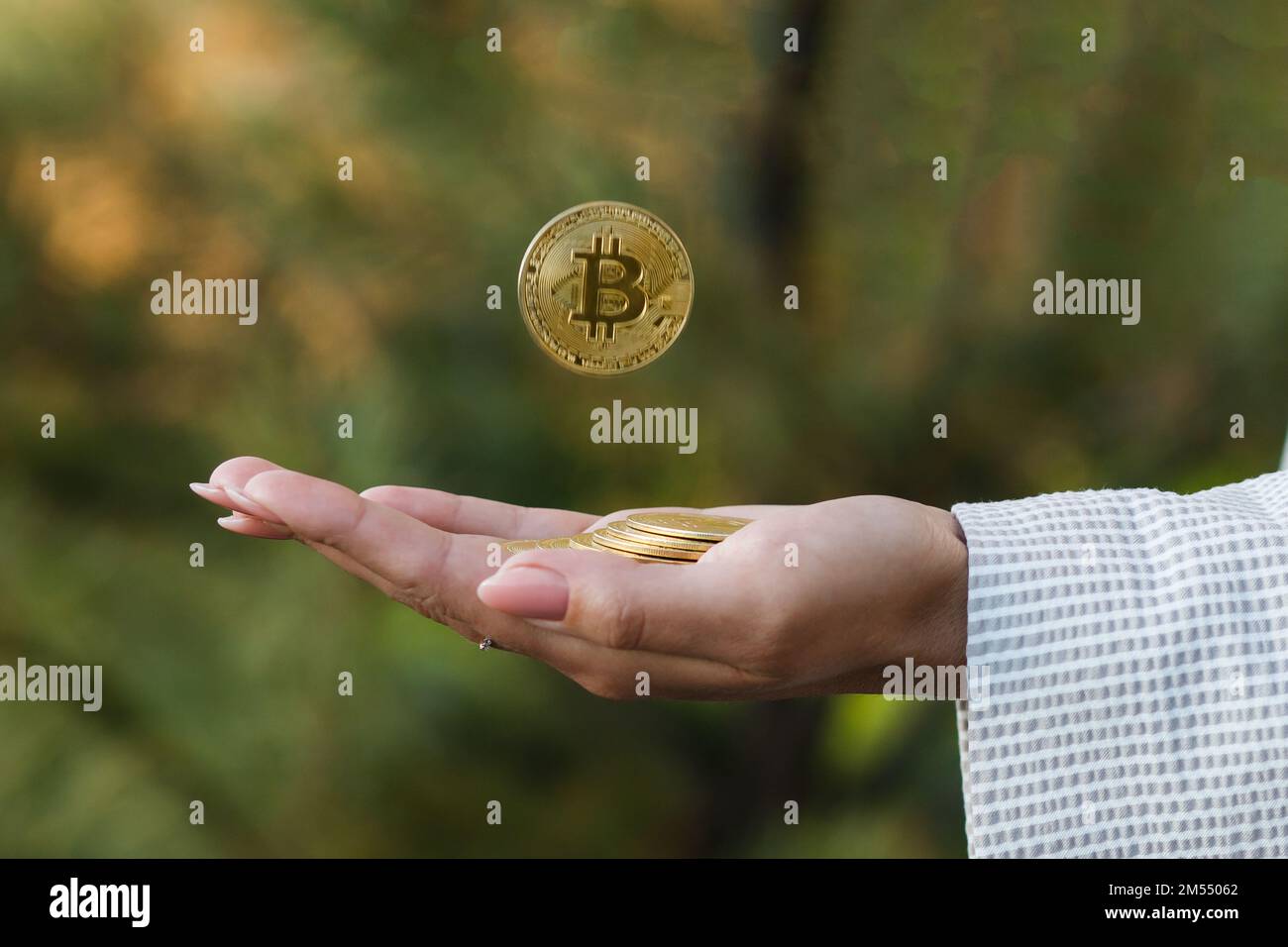 Bitcoin falling concept. Close up of a female hand holding a coin and ...
