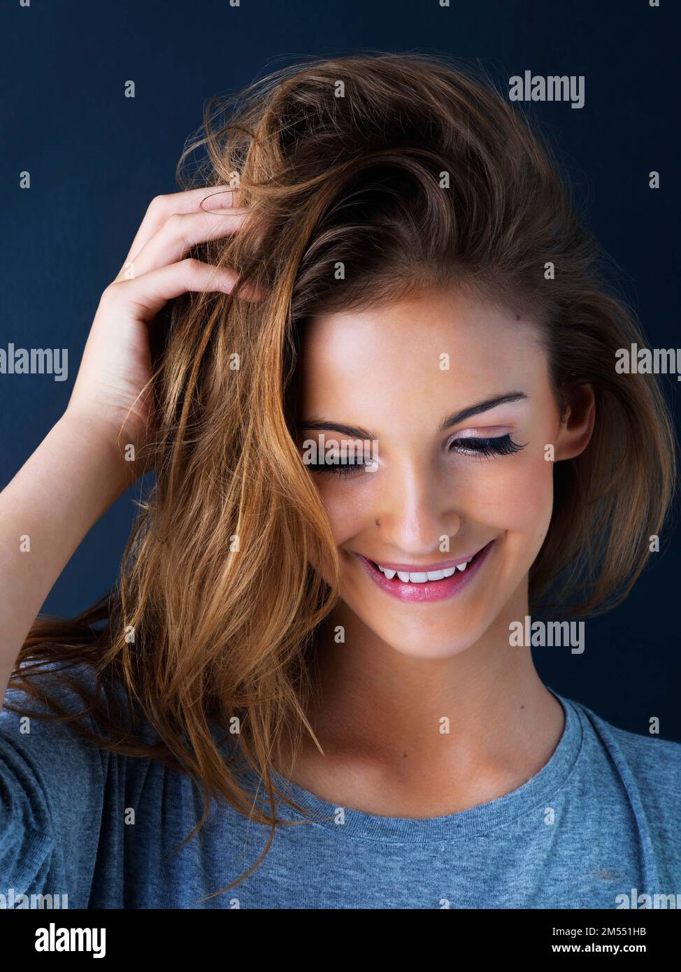 Cute and coy. Studio shot of a cute teenage girl with her hand in her ...