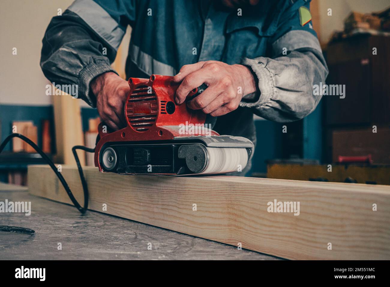 Professional woodworker grinds wooden bar on workbench in carpentry ...