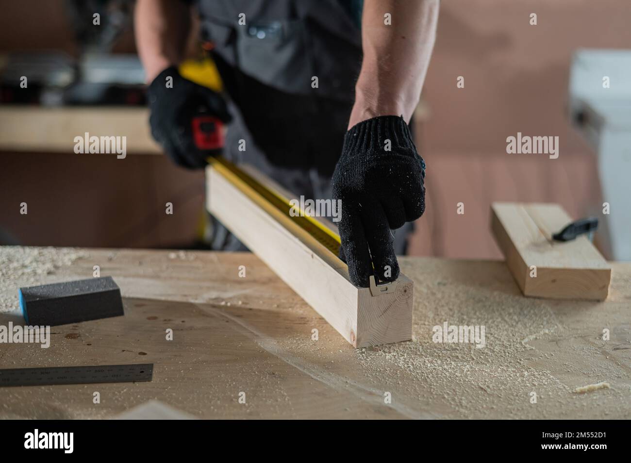 Carpenter measures a wooden board while working in a workshop Stock ...