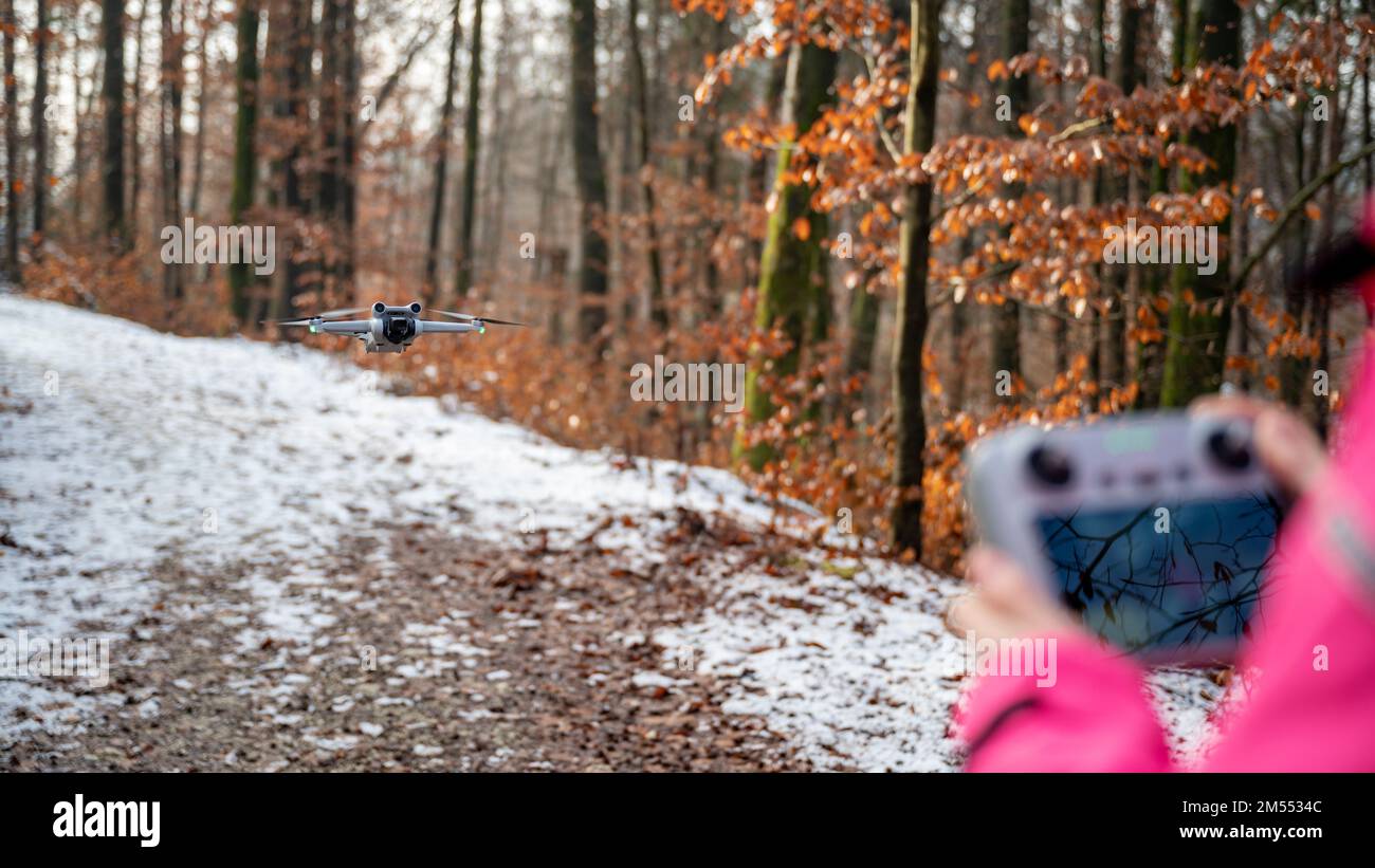 Rear view of a woman managing a drone floating in front of her with ...