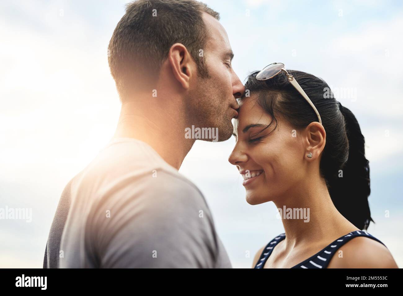 True love is a kiss on the forehead. a young man affectionately kissing ...
