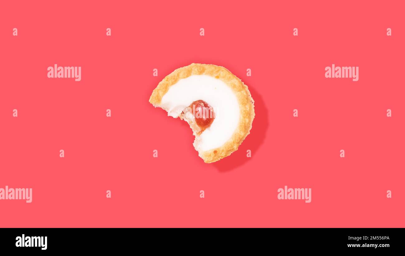 A bitten cherry tart isolated on a pink background Stock Photo - Alamy