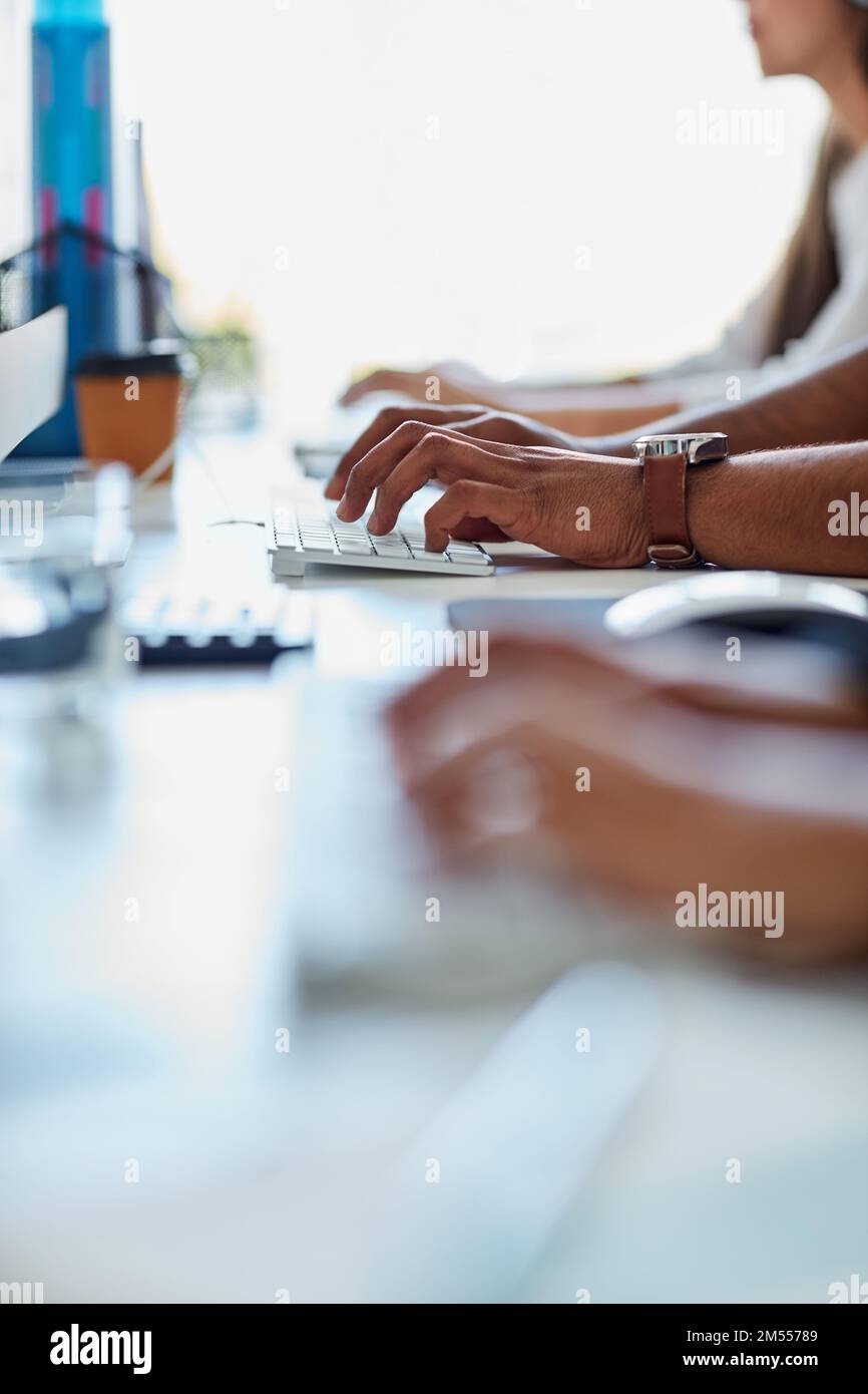 Typing away. a group of workers sitting at their desk Stock Photo - Alamy