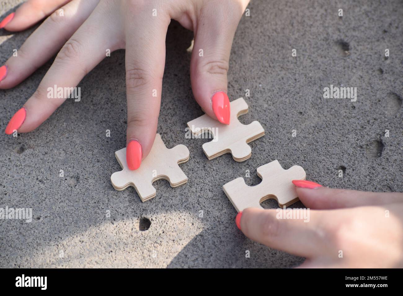 A top view of female hands in coral manicure connecting three wooden ...