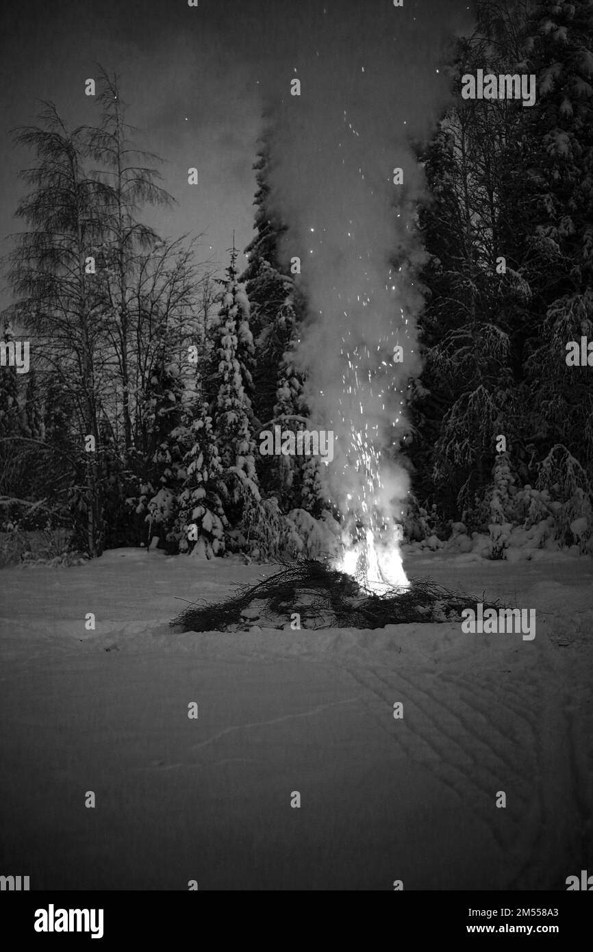 Black and white shot of bonfire with big column of smoke in the snow ...