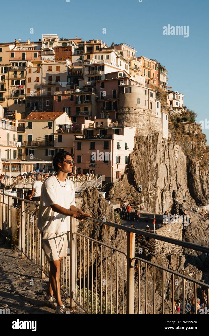 A young man overlooking the rocky coast against the village and cliff ...