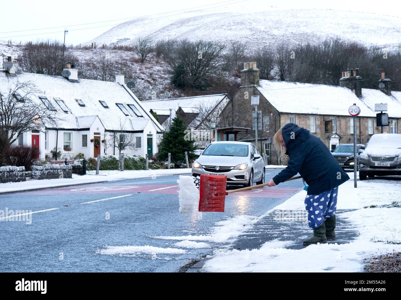 A resident in Carlops in the Scottish Borders clears snow from the ...