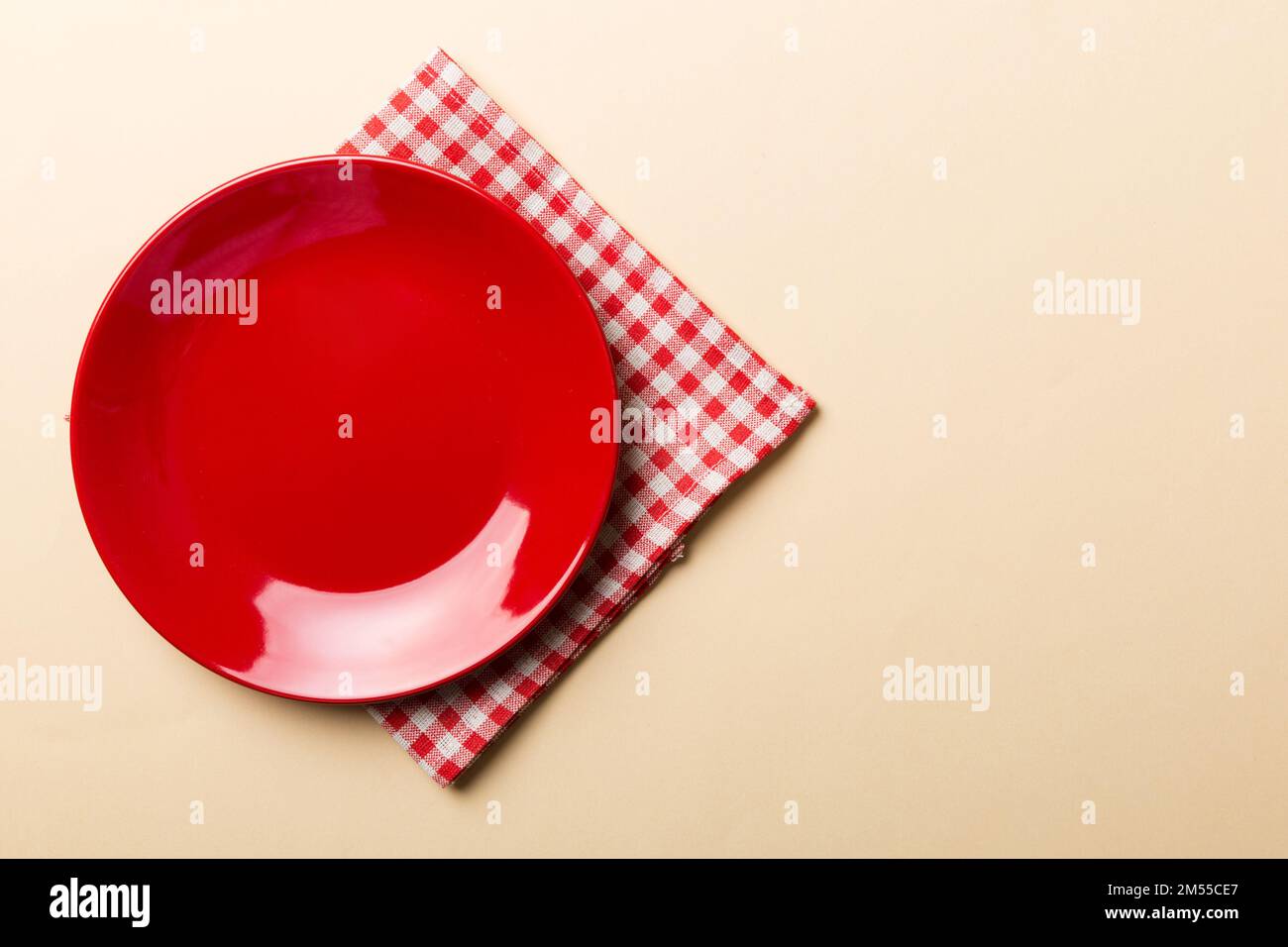 Top view on colored background empty round red plate on tablecloth for ...