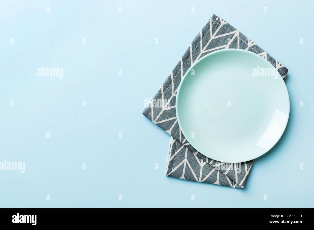 Top view on colored background empty round Blue plate on tablecloth for ...
