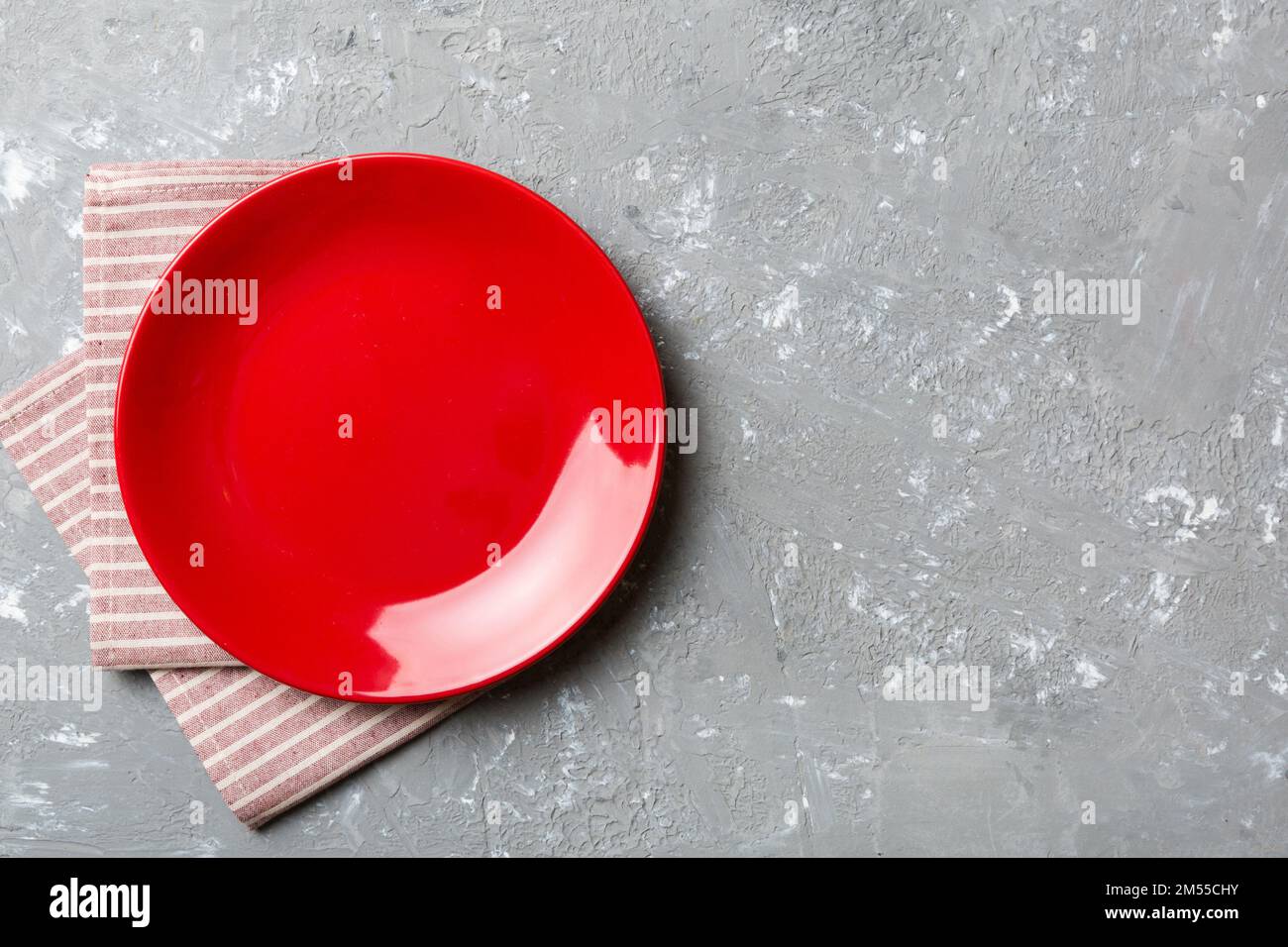 Top view on colored background empty round red plate on tablecloth for ...