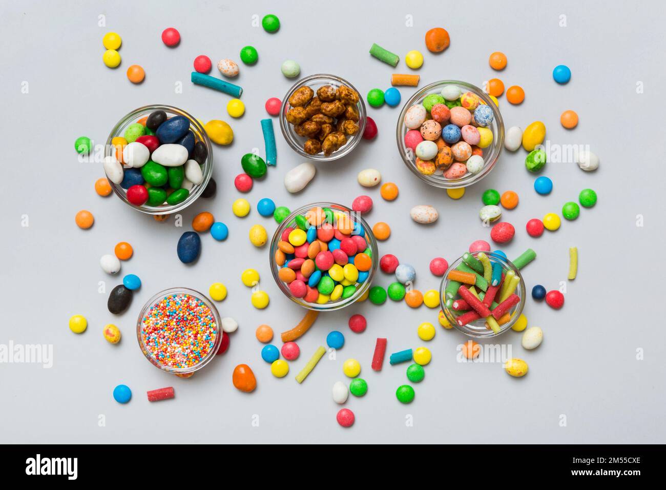 different colored round candy in bowl and jars. Top view of large ...
