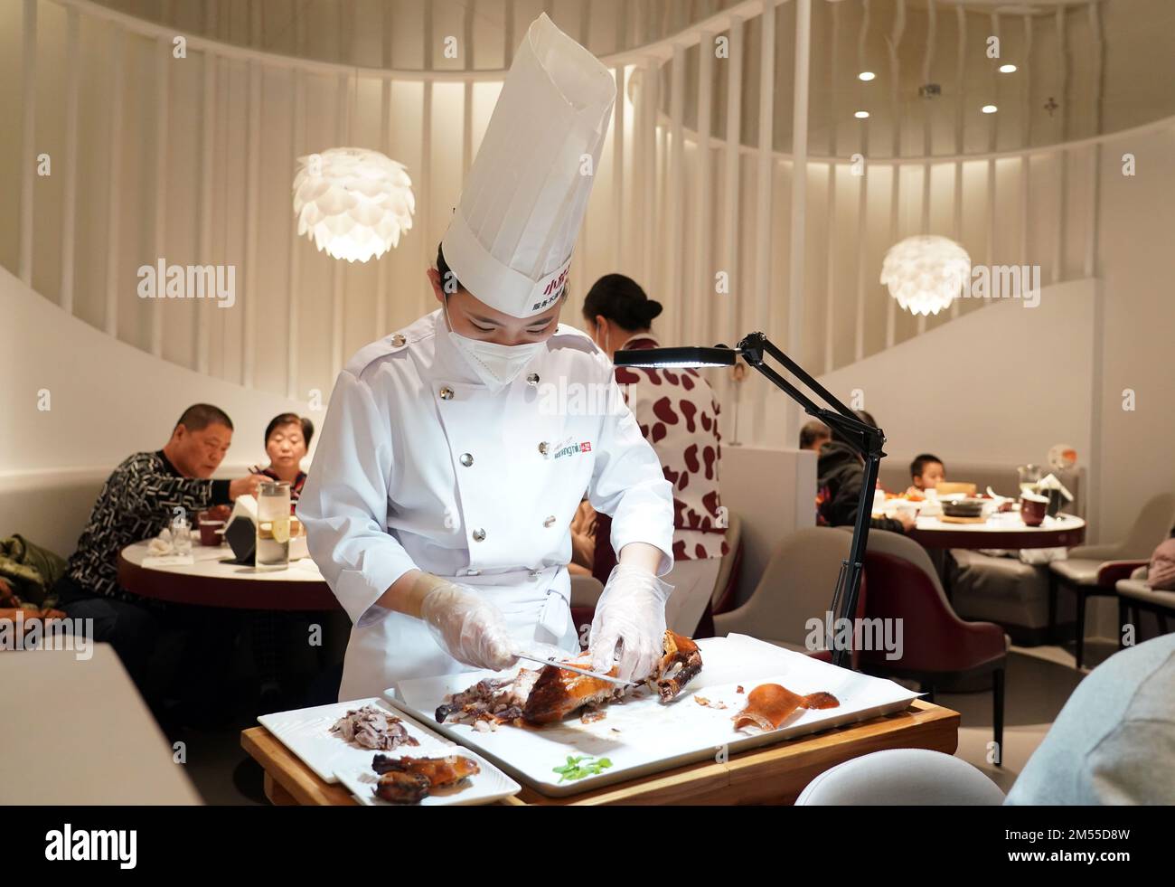 Beijing, China. 25th Dec, 2022. A cook serves roast duck for customers ...