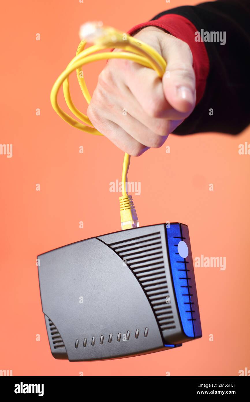 old adsl modem hanging on a cable in a person's hand on a colored ...