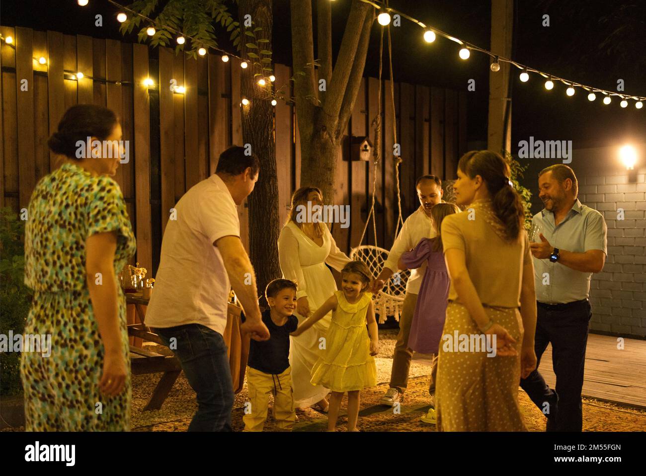 Bride and groom dancing first dance in front of best friends and kids ...
