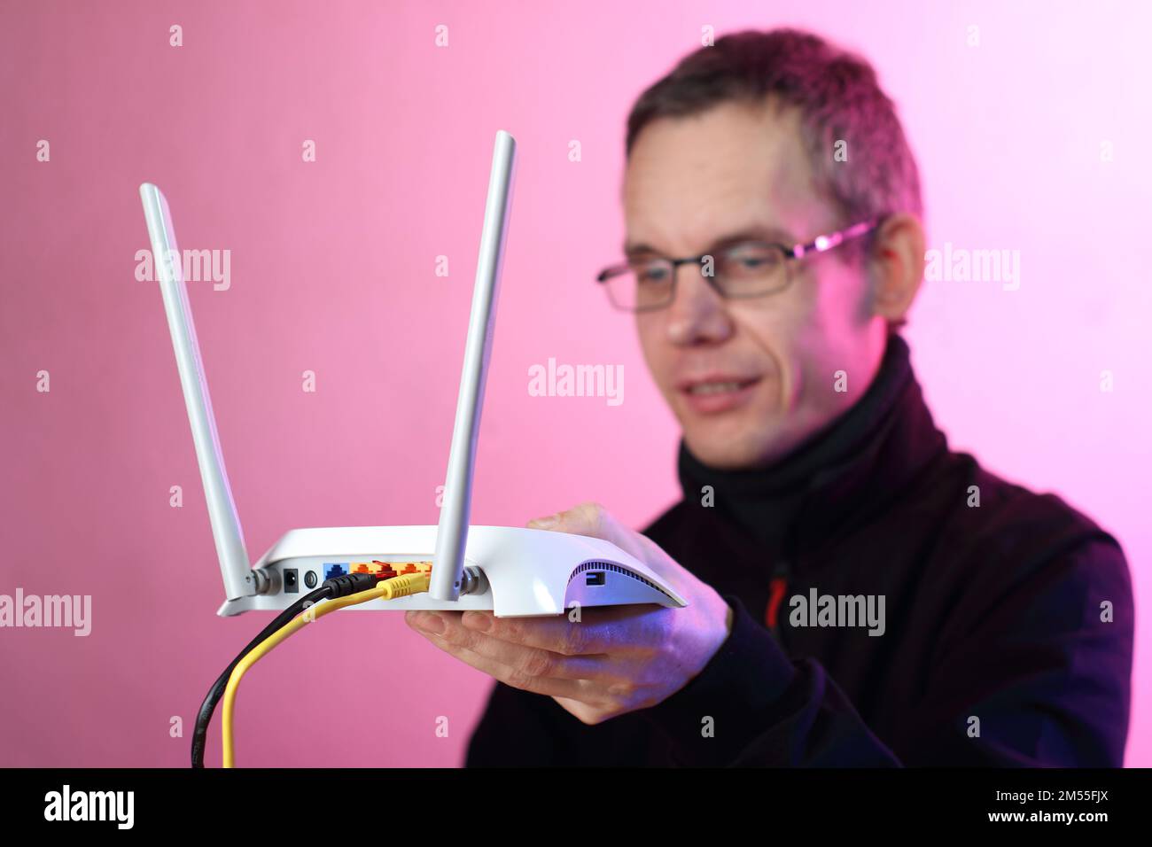 a person holding a white router with two antennas on a pink background ...