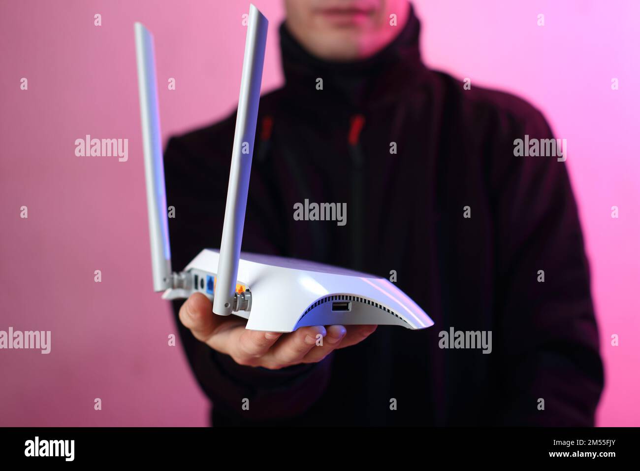 a person holding a white router with two antennas on a pink background ...