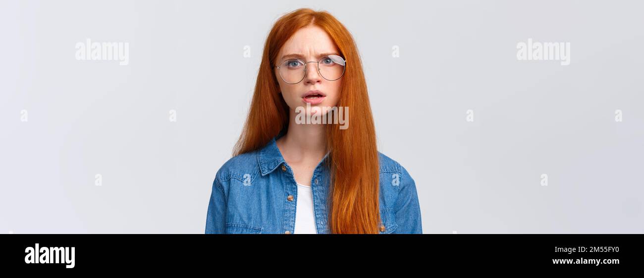Confused and displeased, unsure redhead girl in glasses having ...