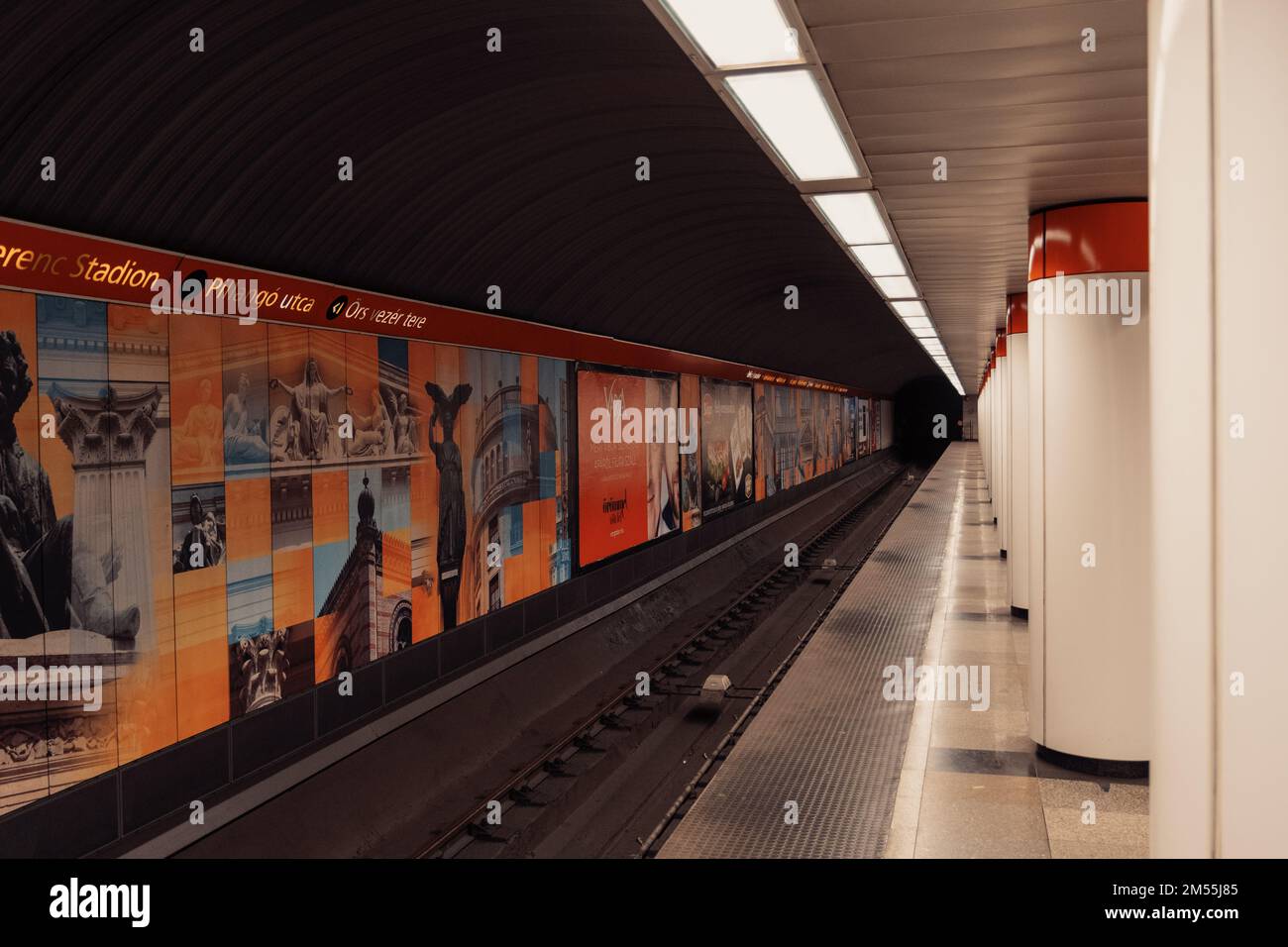 An empty subway platform with pictures of landmarks on the walls in ...