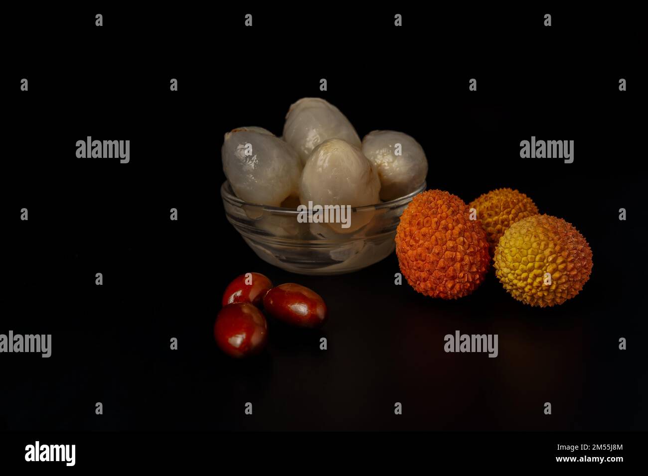 whole fresh lychees, peeled and with their bones on a black background ...