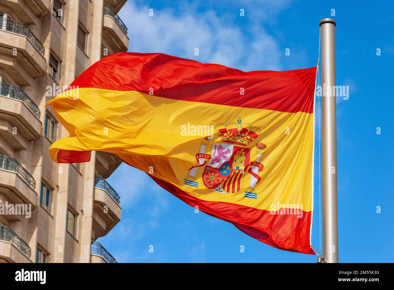 Closeup of a Spanish flag blowing in the wind against a clear blue sky ...