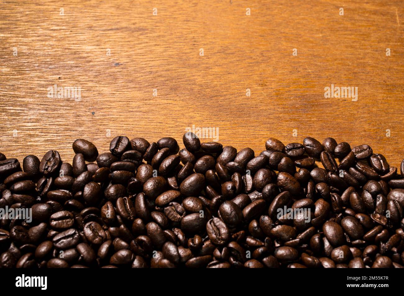 A closeup of roasted coffee beans on a wooden background Stock Photo ...