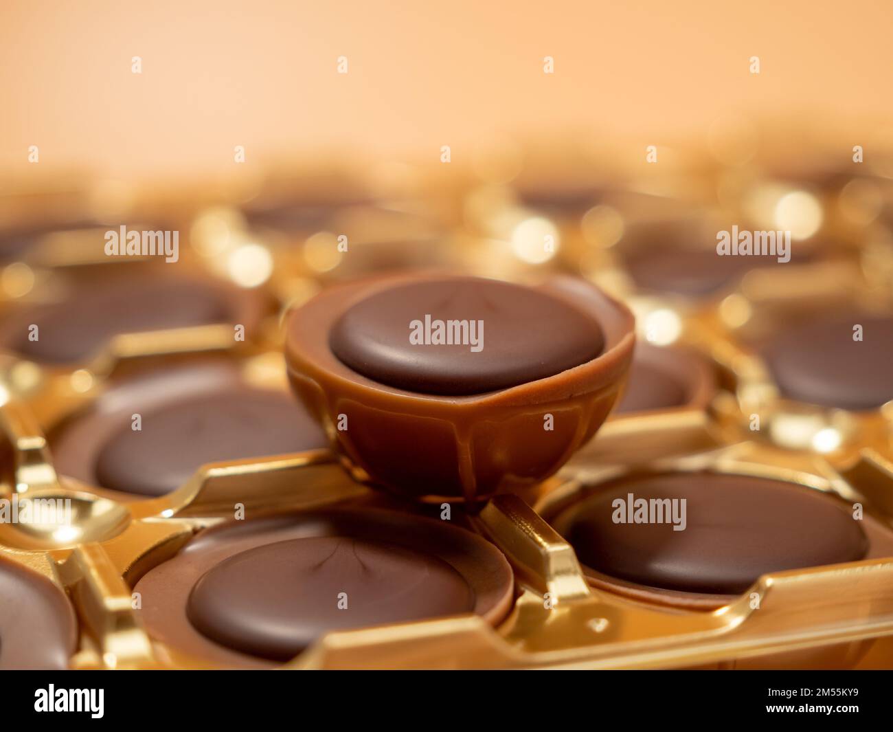 Chocolate candies on an orange background. Sweets with caramel. Round ...